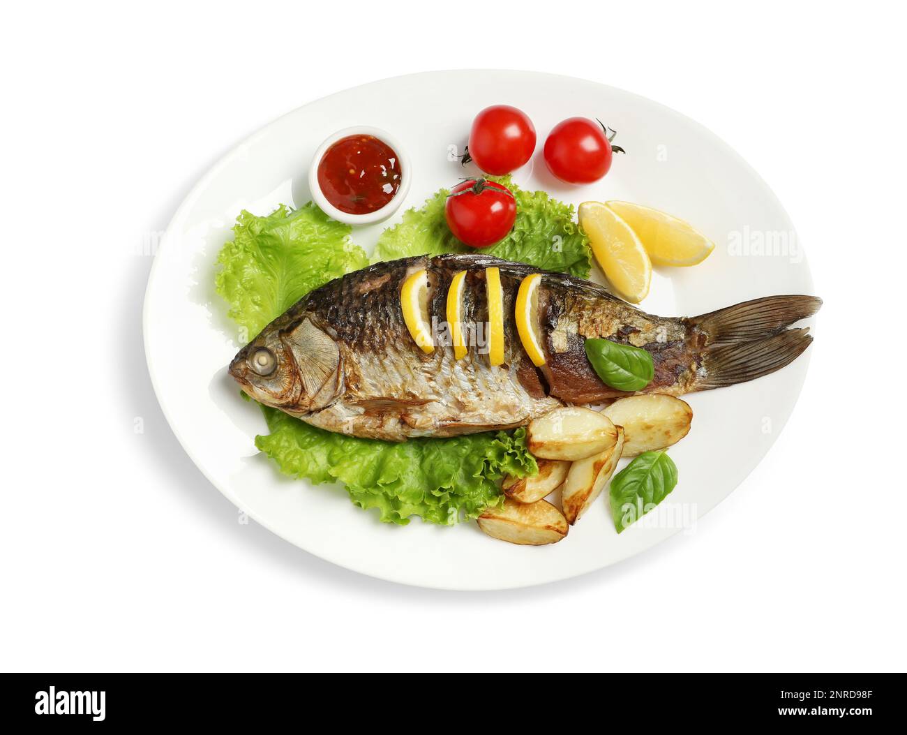 Tasty homemade roasted crucian carp with garnish on white background ...