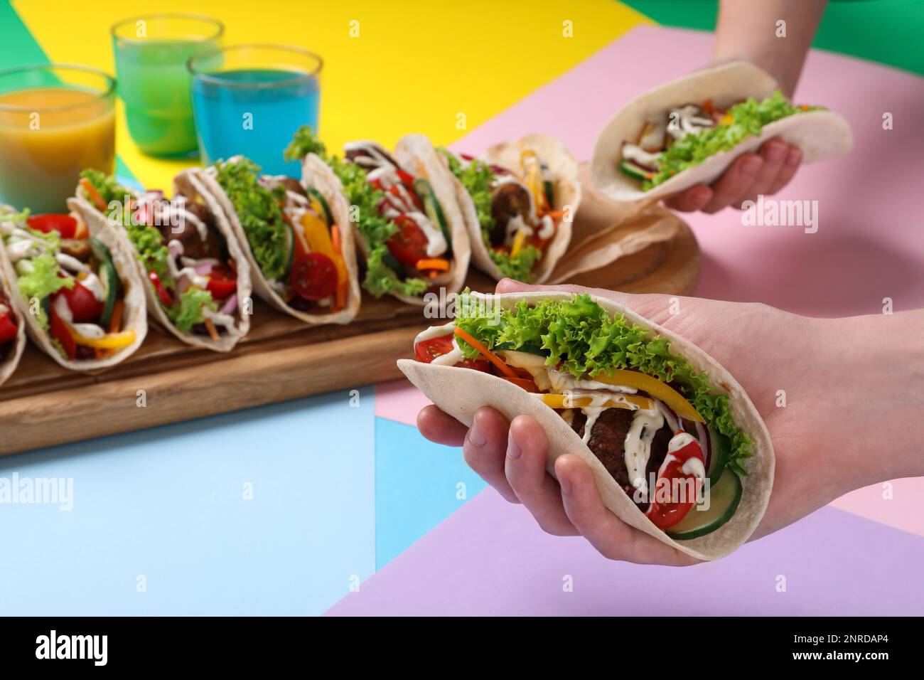 Woman holding delicious taco against color background, closeup. Space ...