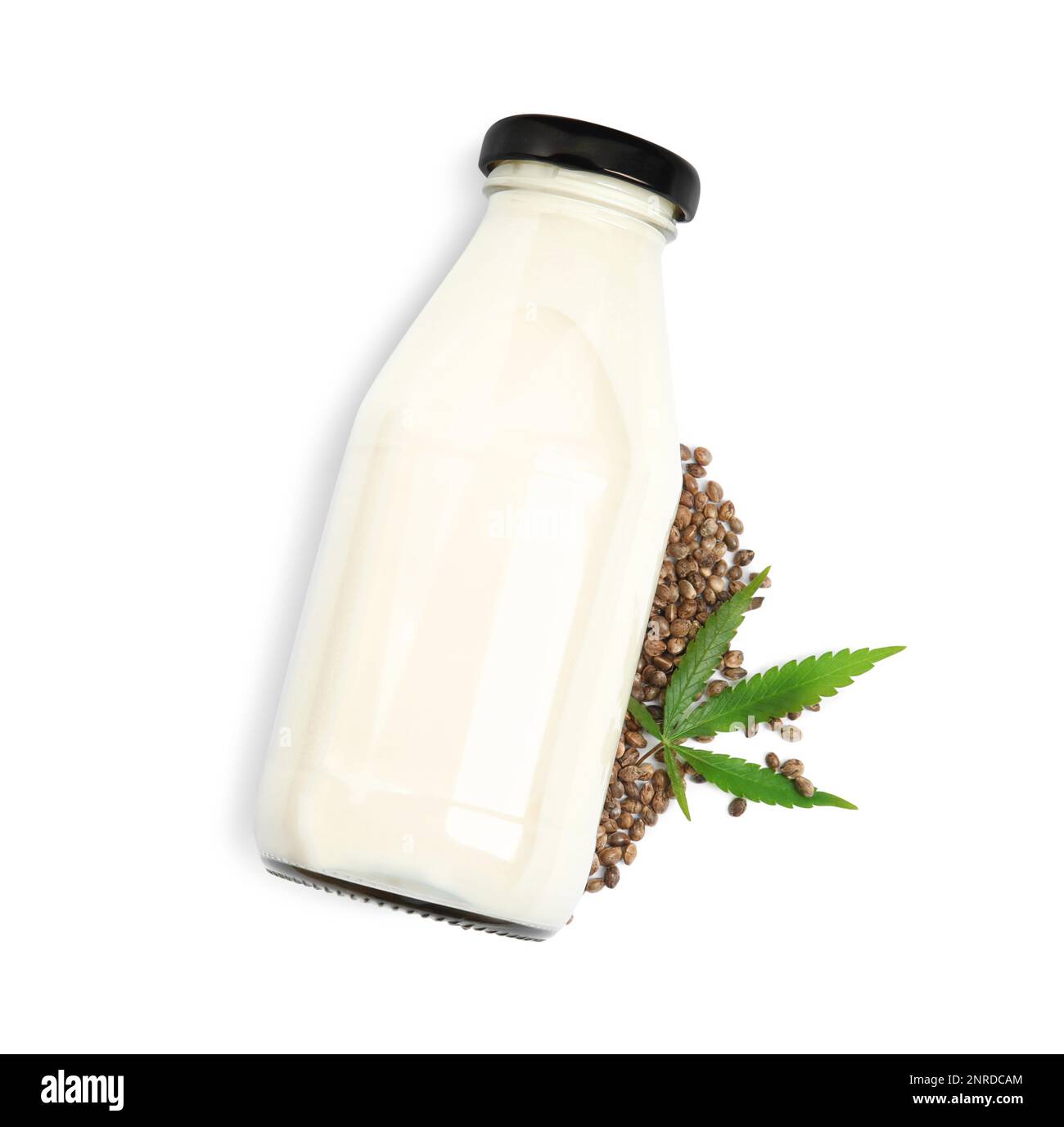 Glass bottle of hemp milk, leaf and seeds on white background, top view ...