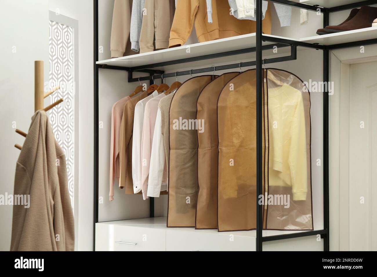 Garment bags with clothes on rack in dressing room Stock Photo - Alamy