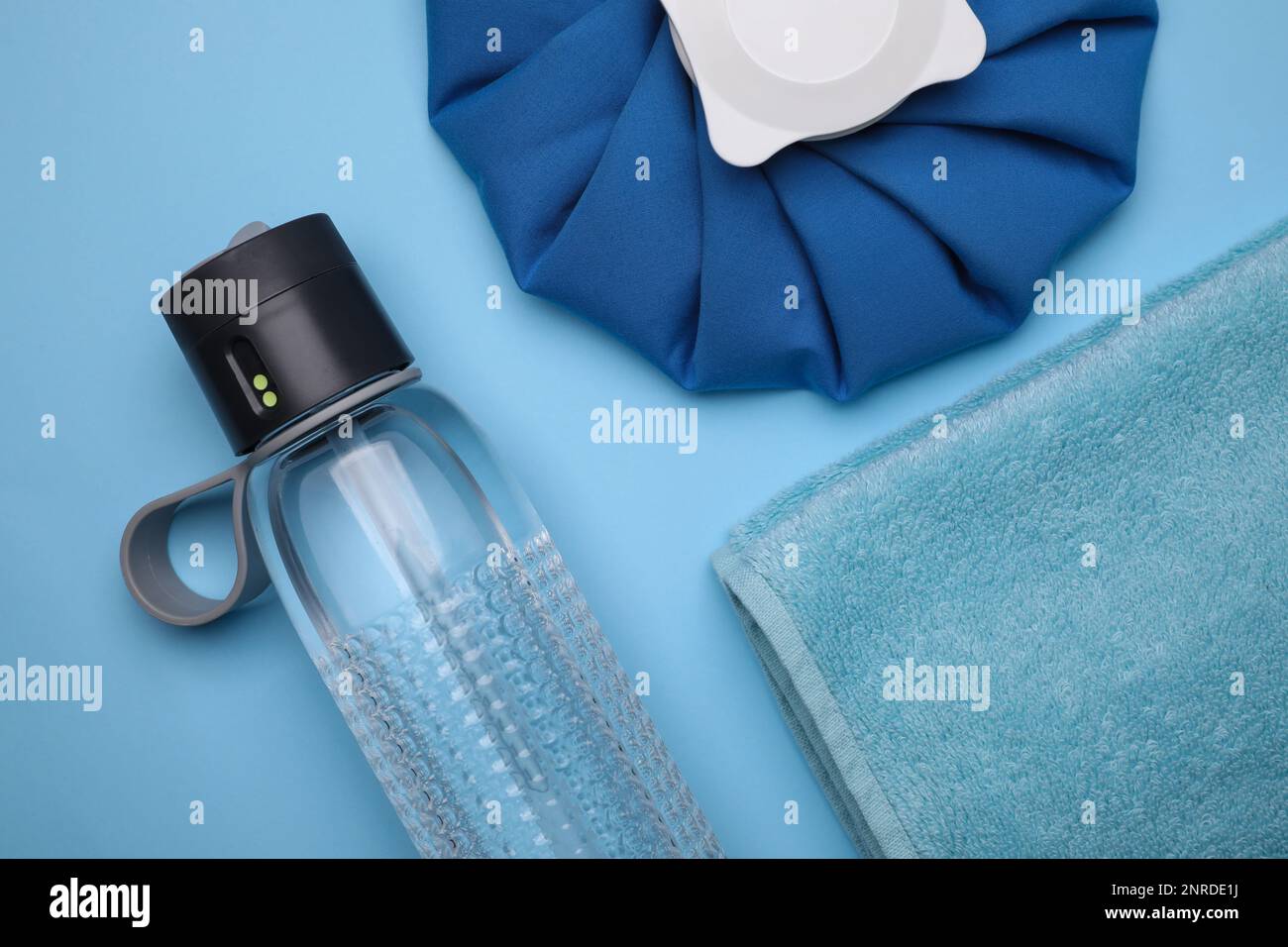 Bottle of water, cold compress and towel on light blue background, flat ...