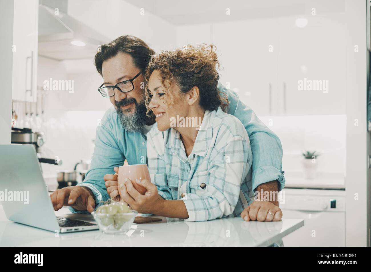 Love modern couple man and woman using together a laptop in the kitchen ...