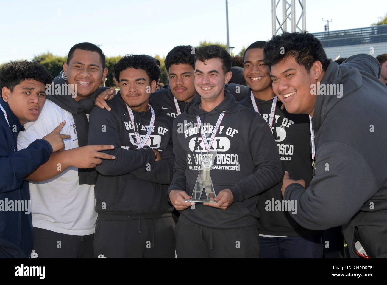 Members of the St. John Bosco Braves football team pose with a trophy ...