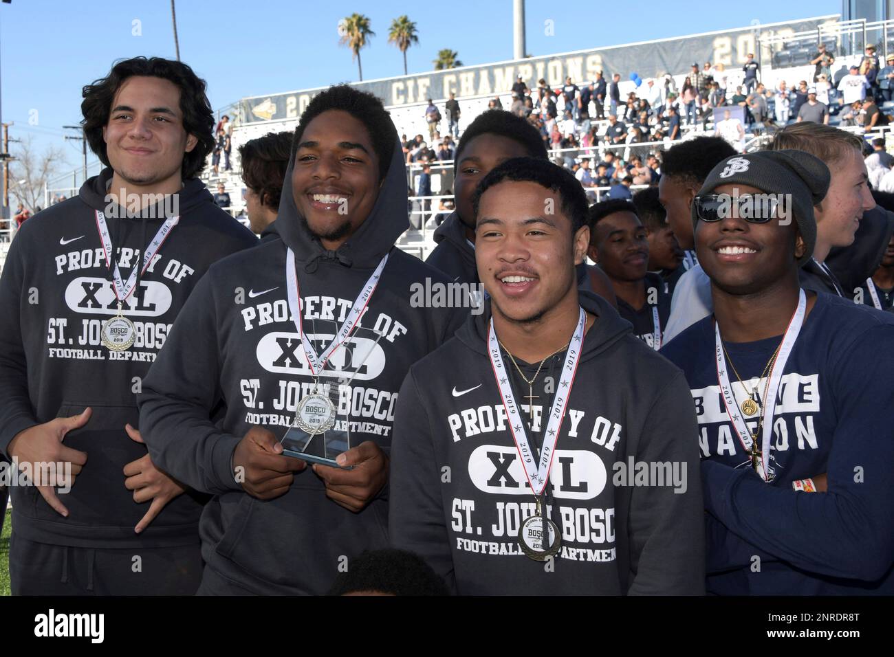 Members of the St. John Bosco Braves football team pose with a trophy ...