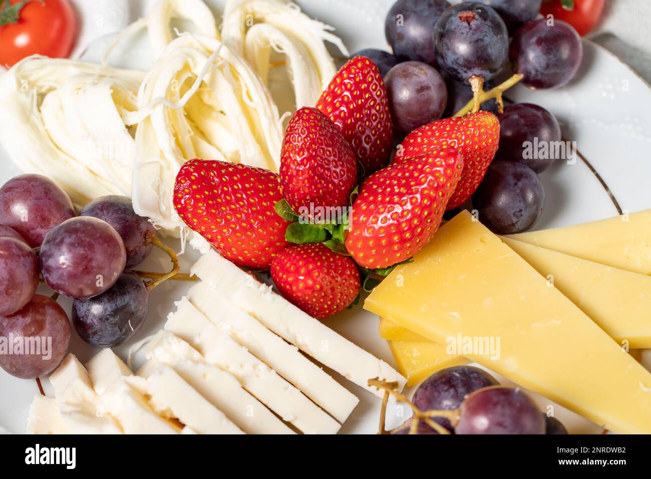 Cold cheese plate, cheese set platter. Strawberry, grape and cheese assortment on gray ...
