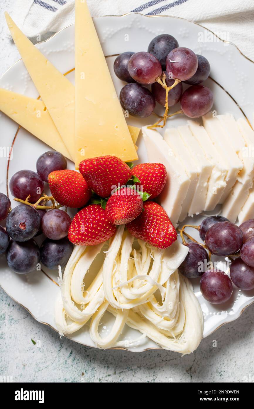 Cold cheese plate, cheese set platter. Strawberry, grape and cheese assortment on gray ...