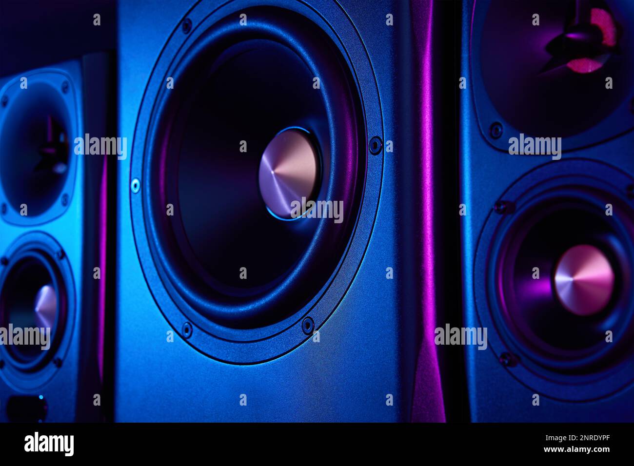 Two sound speakers and subwoofer on dark background with neon lights ...
