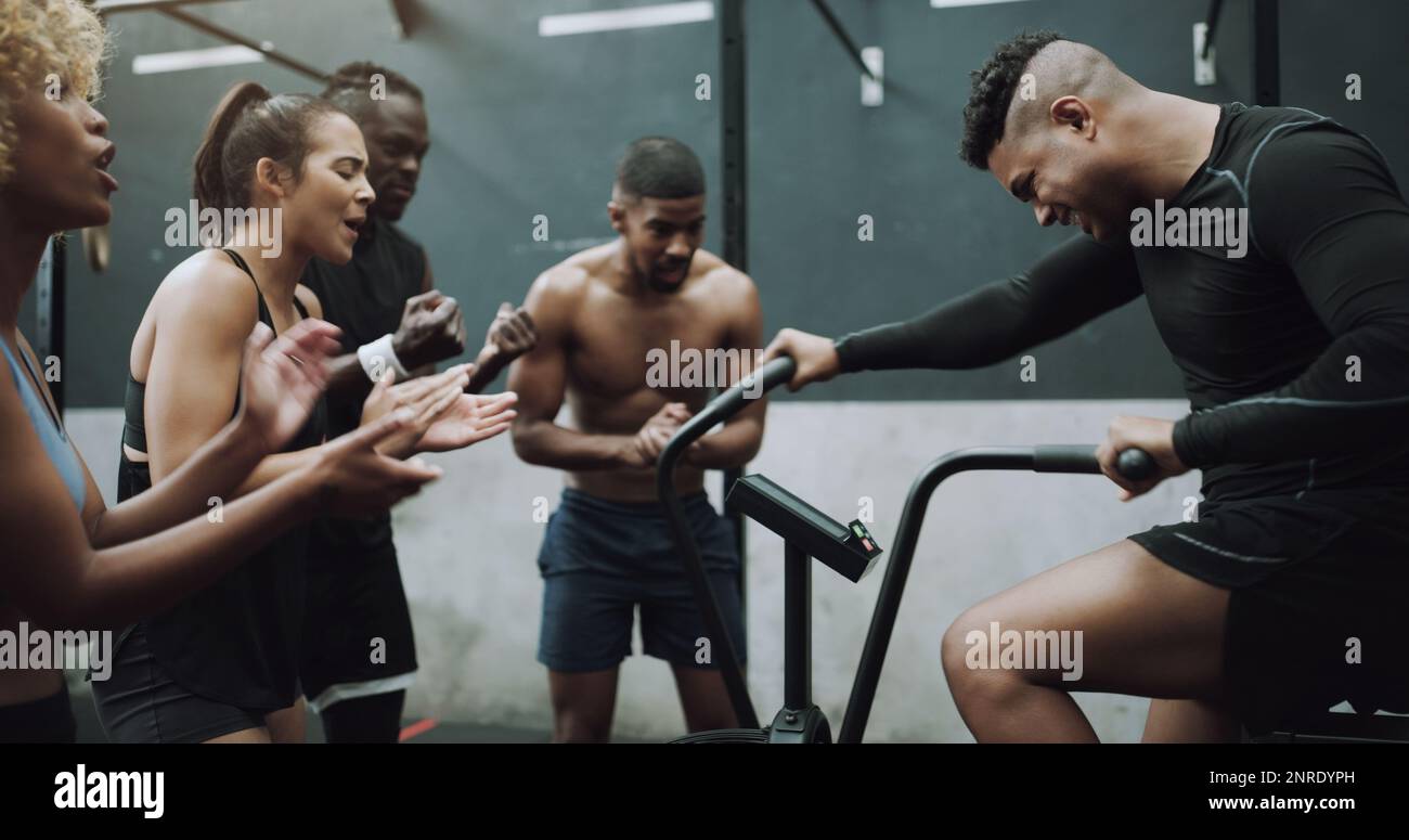 Everyones cheering him on. a young man working out on an exercise bike ...