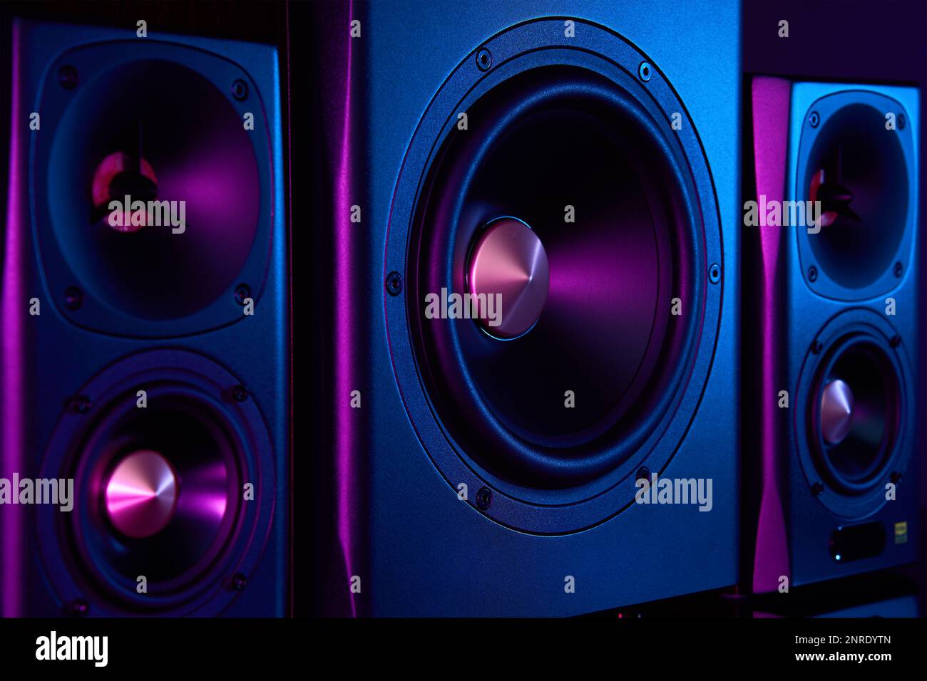 Two sound speakers and subwoofer on dark background with neon lights ...