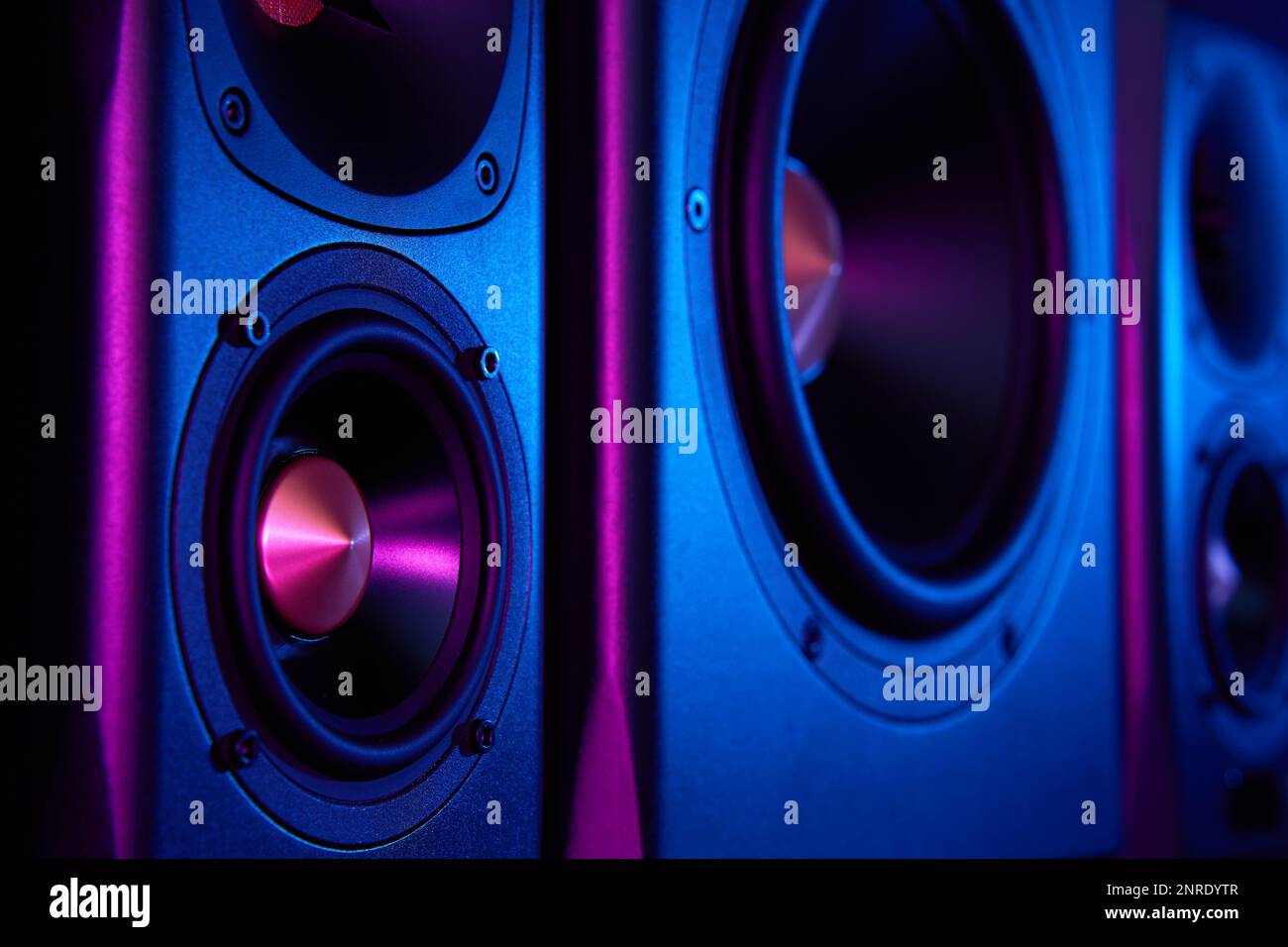 Two sound speakers and subwoofer on dark background with neon lights ...