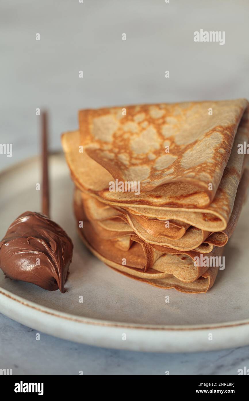 Traditional Russian sweet thin crepes with a spoon of chocolate cream ...
