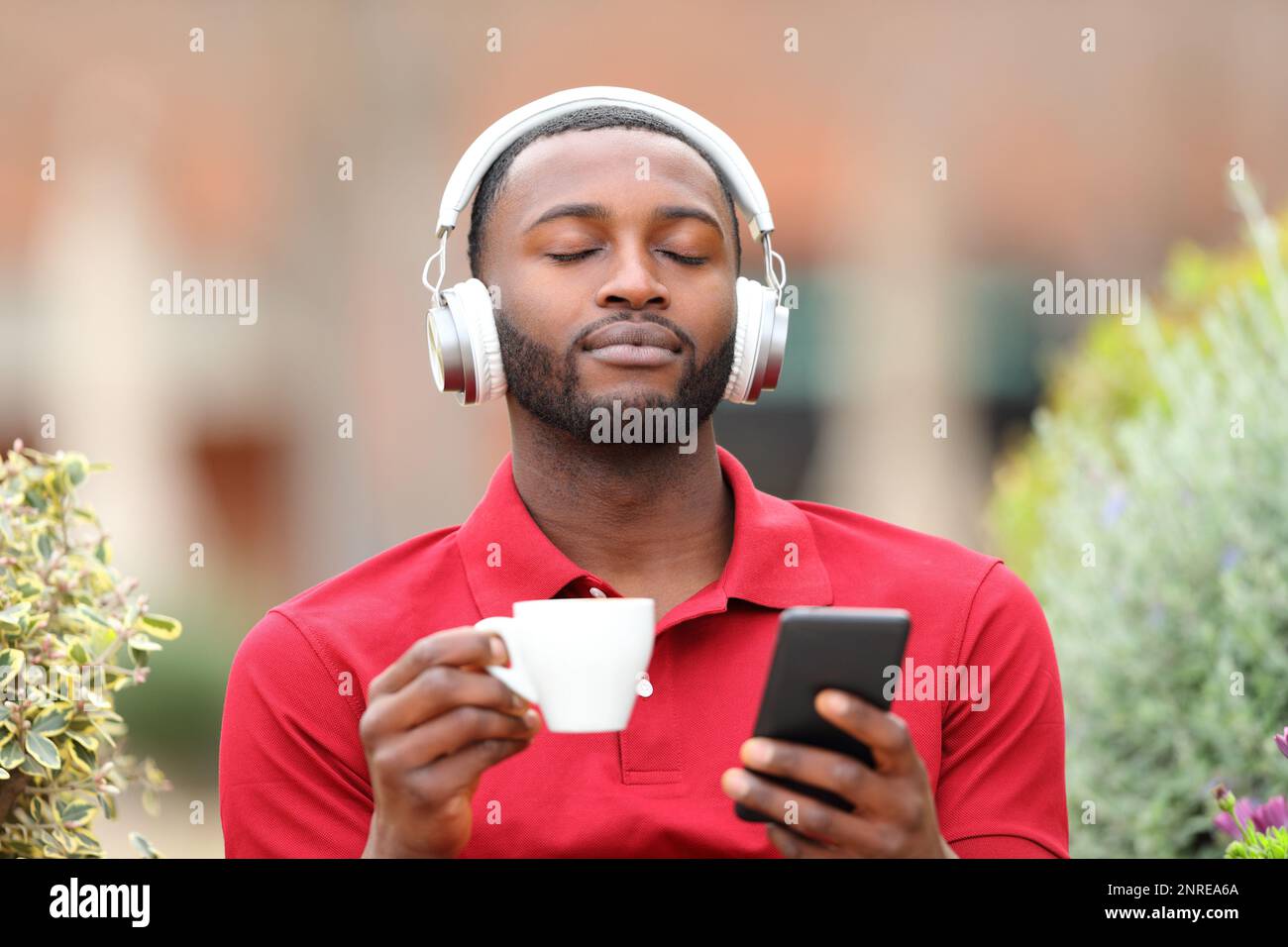 Black man relaxing and breathing listening to music with headphones and ...