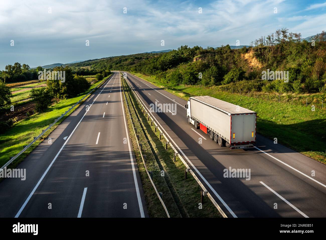 Truck with semi-trailer driving along highway on the sunset background ...