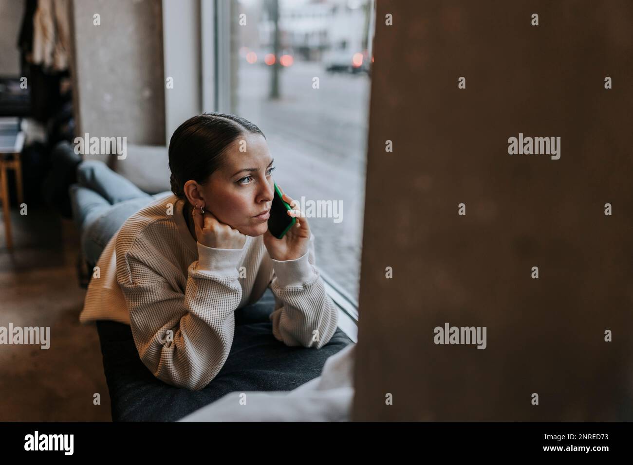 Businesswoman talking over mobile phone while looking out through ...