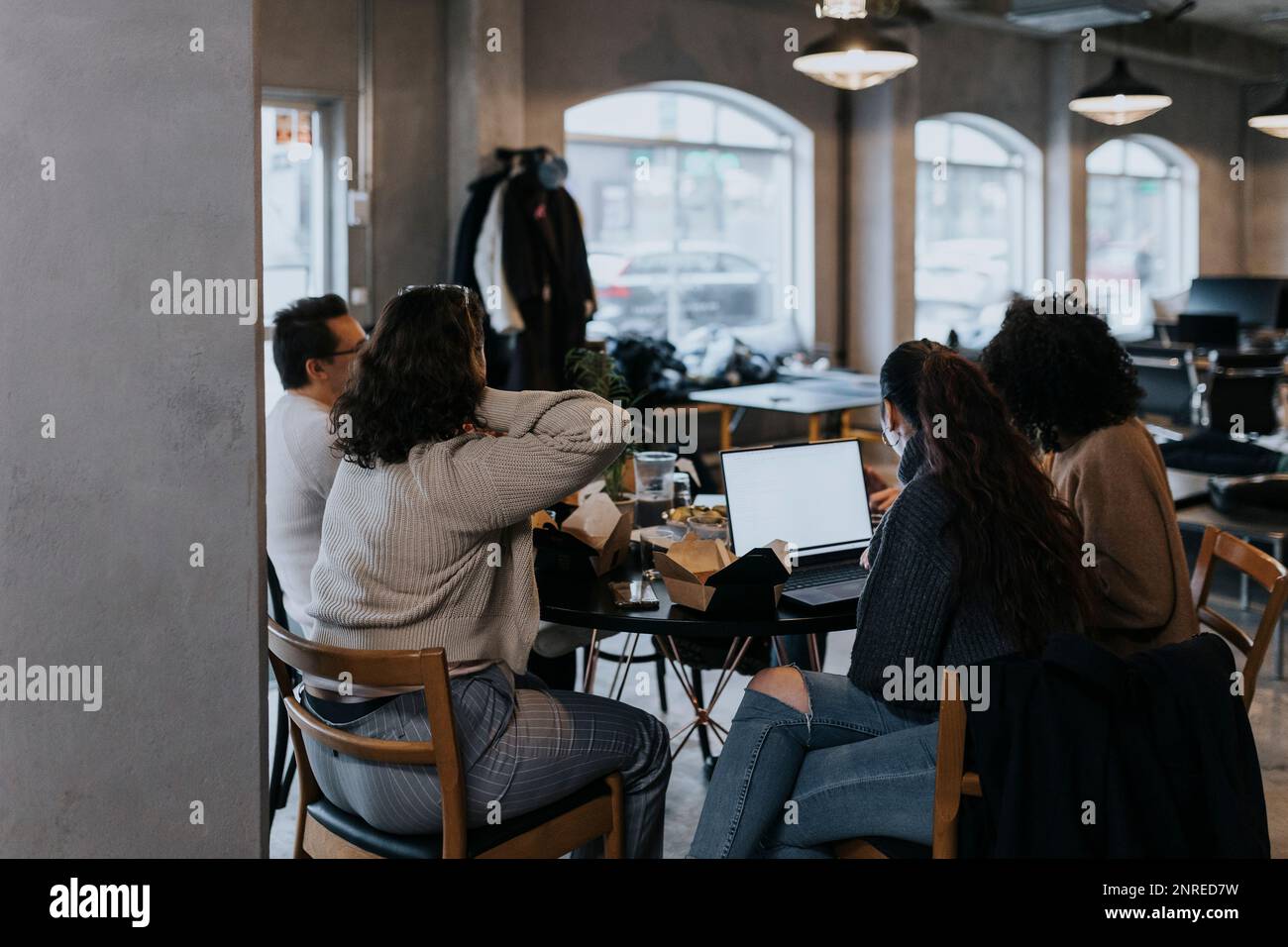 Young programmer working on laptop by male and female colleagues having ...