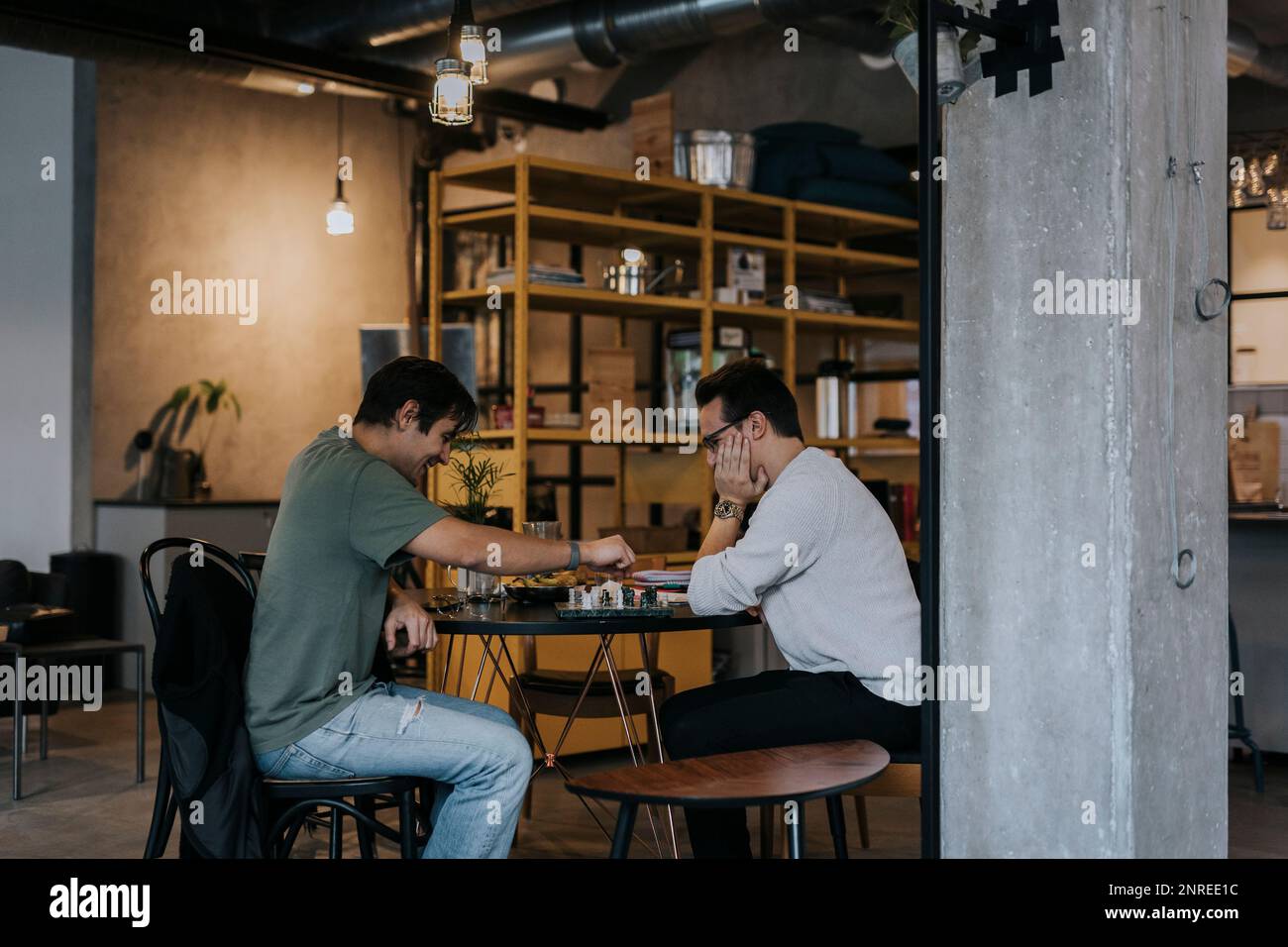 Male business colleagues playing chess on table at office cafeteria ...