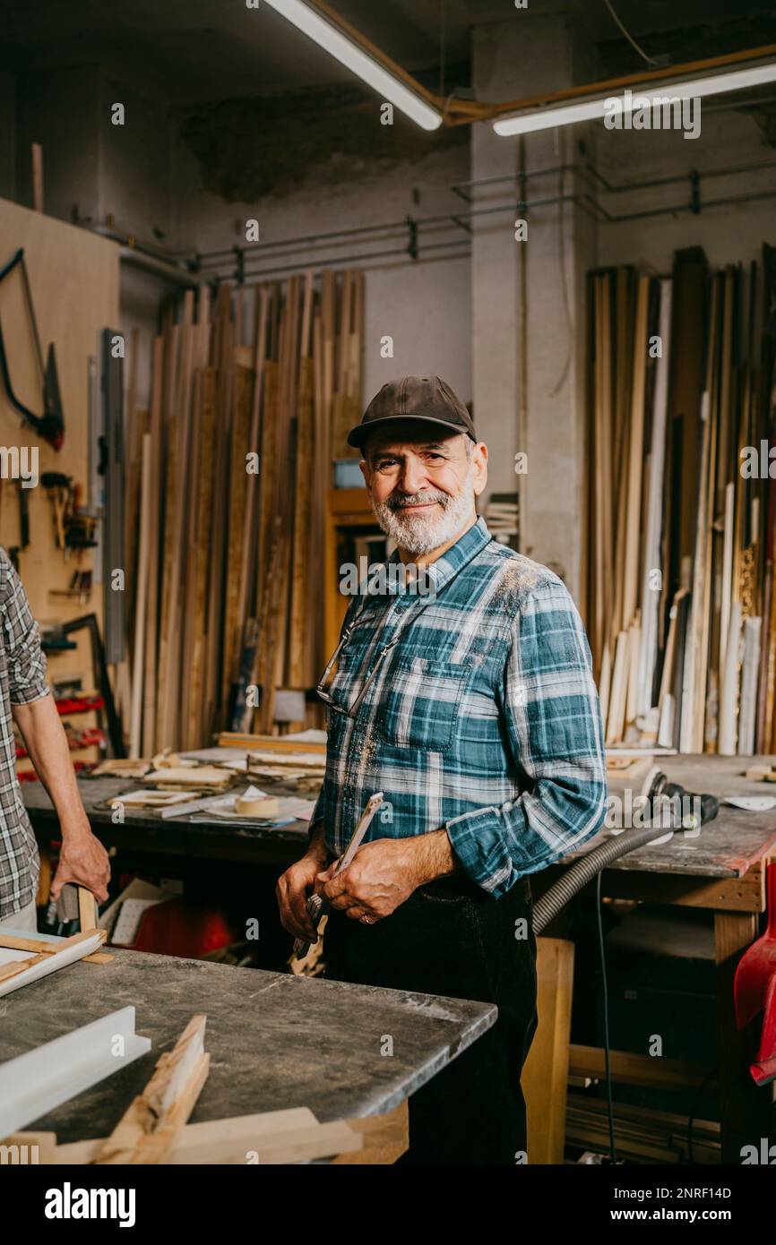 Portrait of smiling senior craftsman standing at workshop Stock Photo ...