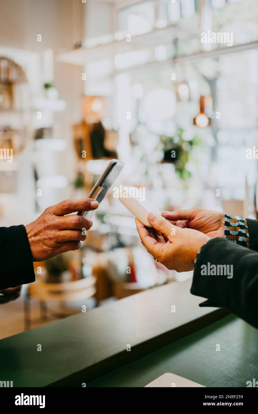 Female owner giving credit card reader to customer while doing online ...