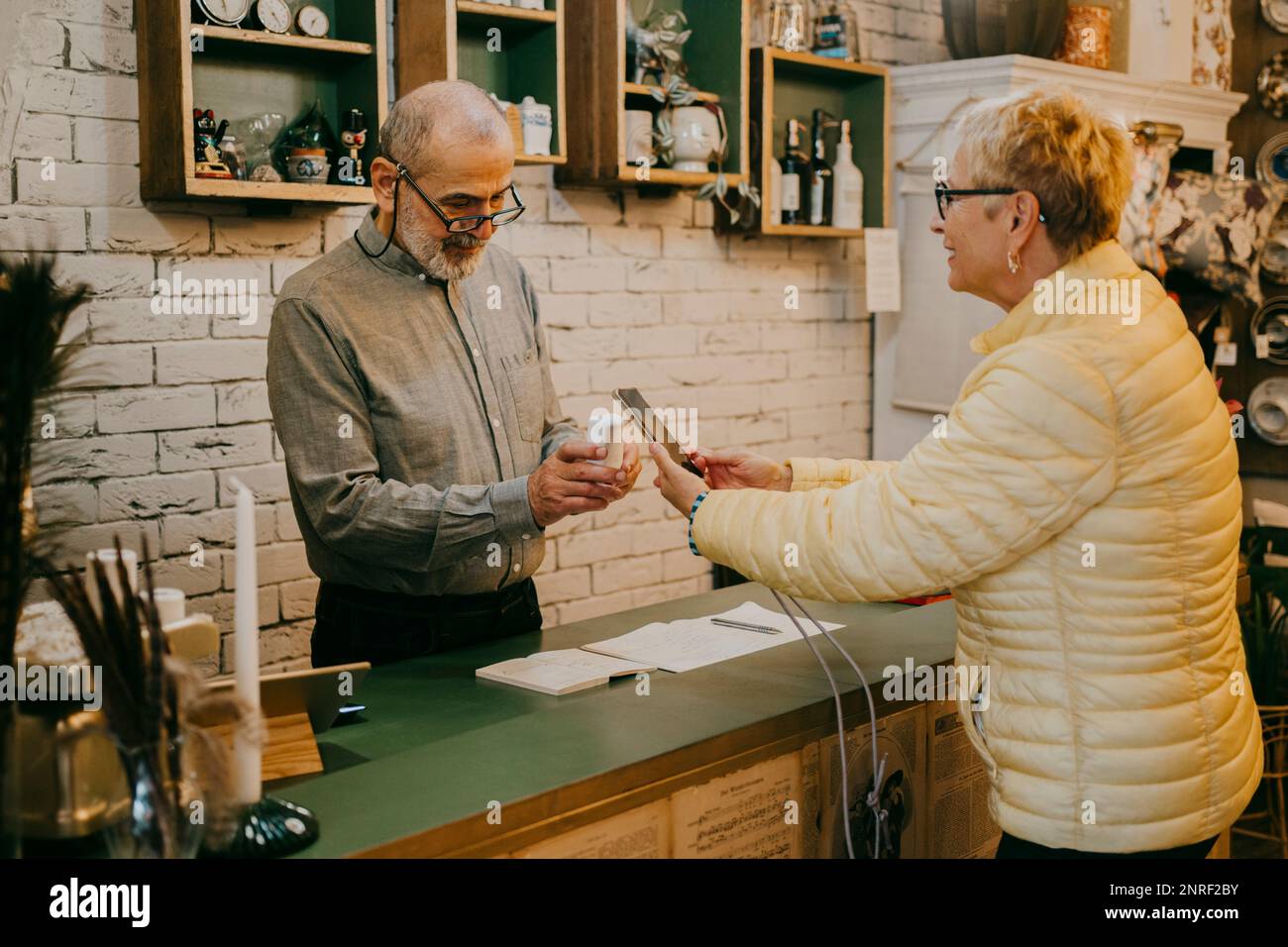 Side view of female customer paying via tap to pay method after ...