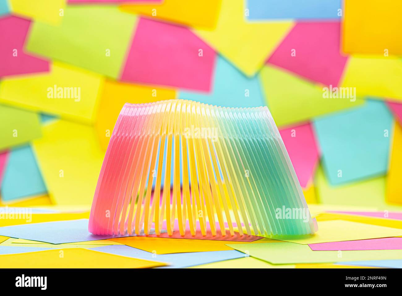 Toy plastic rainbow on a multicolored paper sticky notes on background ...