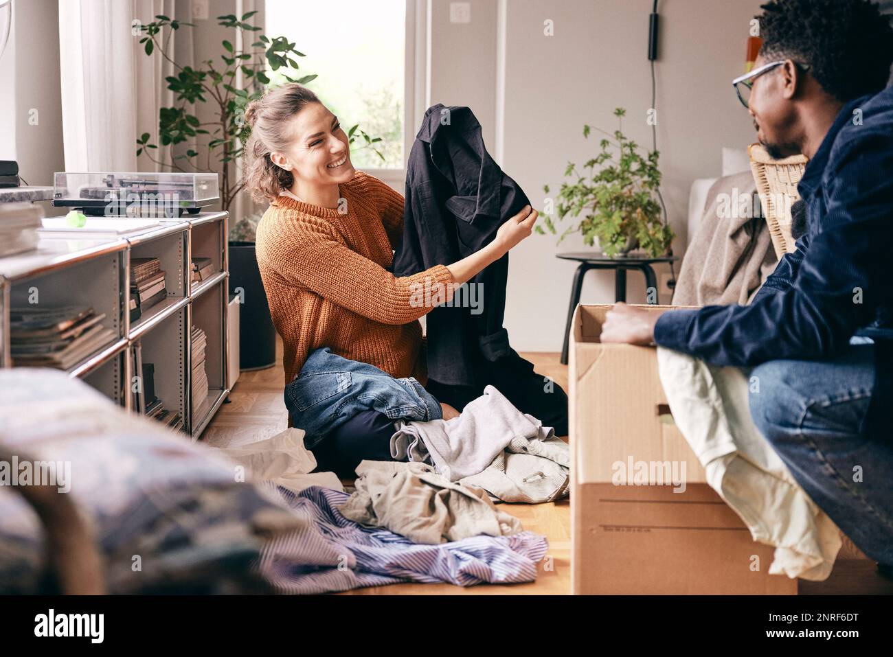Happy woman showing shirt to man while sorting clothes at home Stock ...