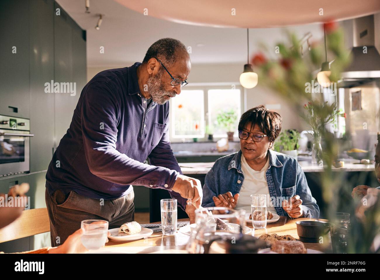 Senior man serving food to woman sitting at dining table in home Stock ...