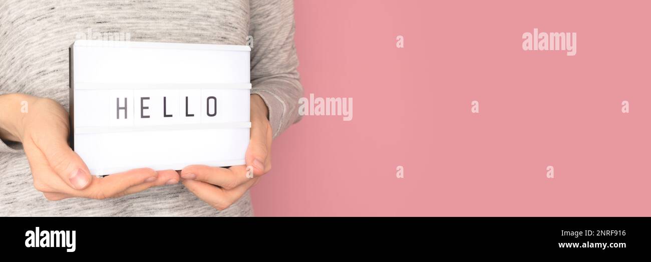 Word Hello. Banner with female hands hold lightbox in front of pink ...