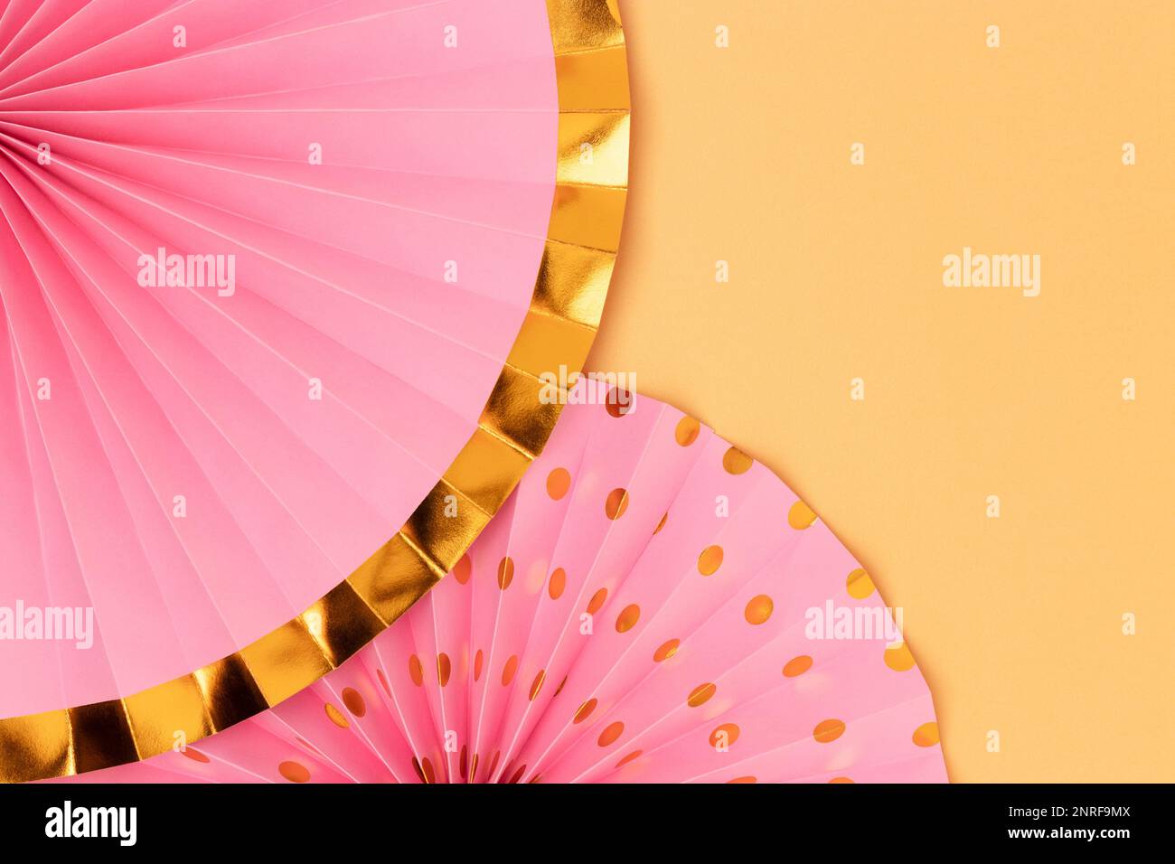 Pink paper fans on a gold glittering background. Creative concept with ...