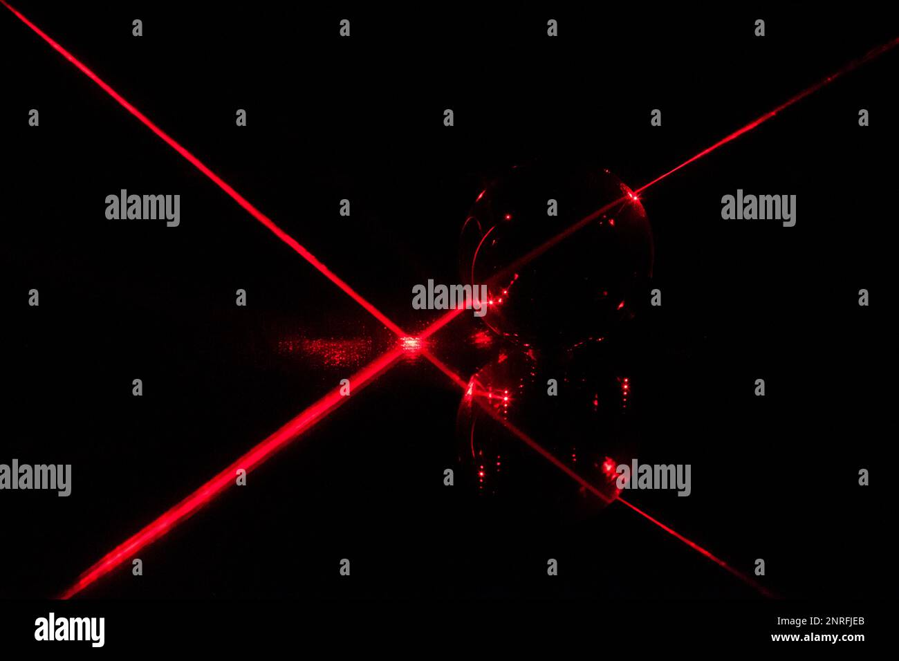 Red laser beam reflecting on a mirror before passing through a glass ...