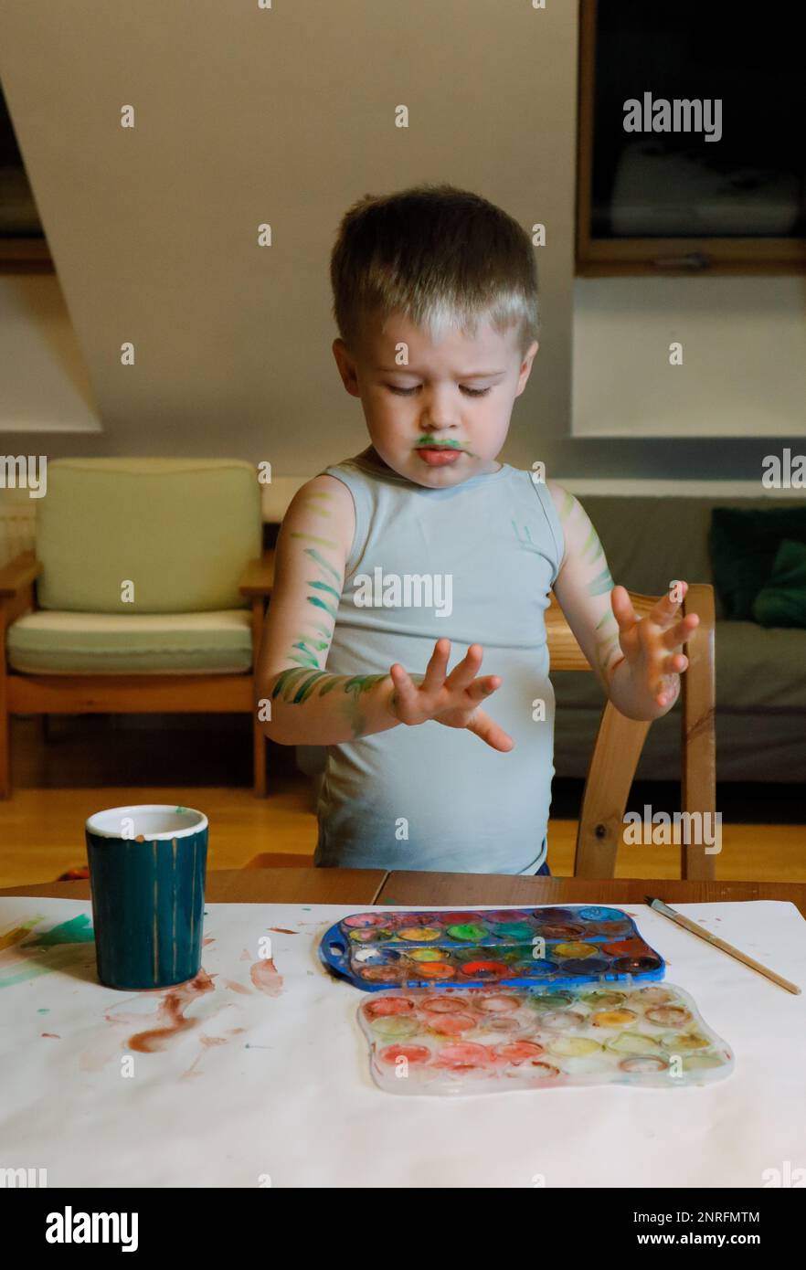 The boy is engaged in creativity - he paints his hands with paint Stock ...