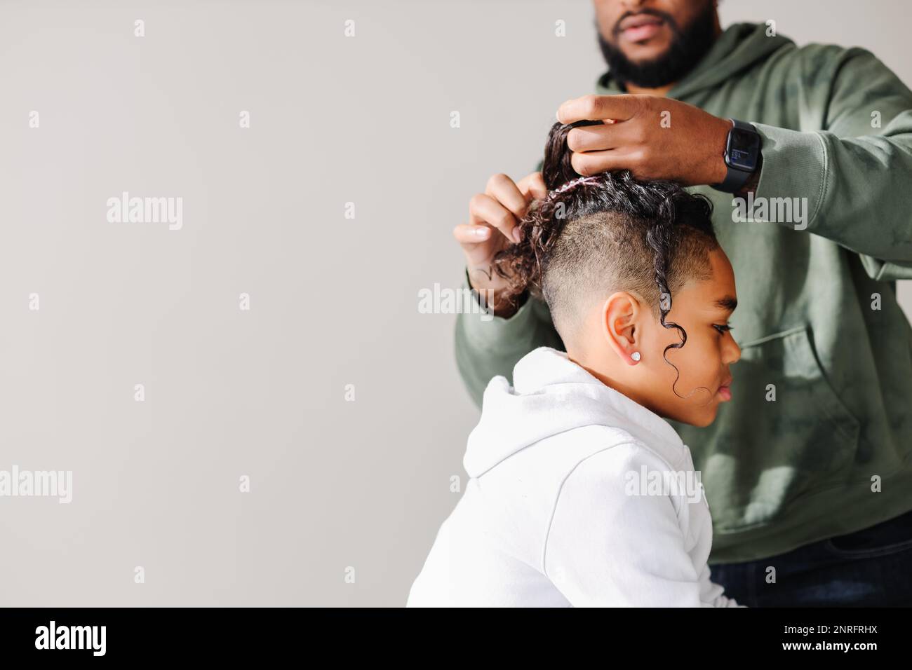 Close up of Black dad doing his son's long hair Stock Photo - Alamy