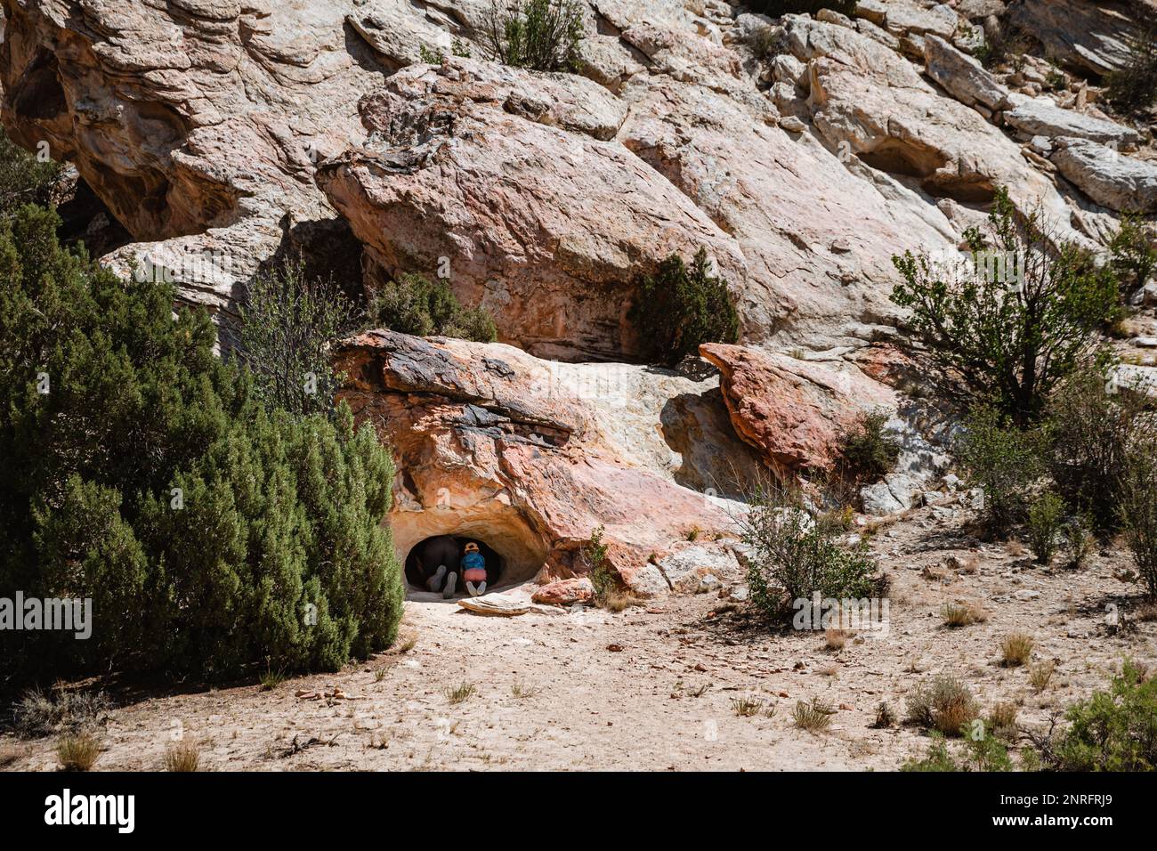 People exploring small cave in Utah desert Stock Photo - Alamy