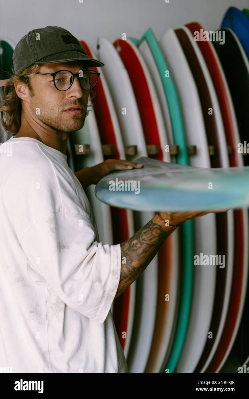 Man choosing a surfboard in a surfboard shop Stock Photo - Alamy