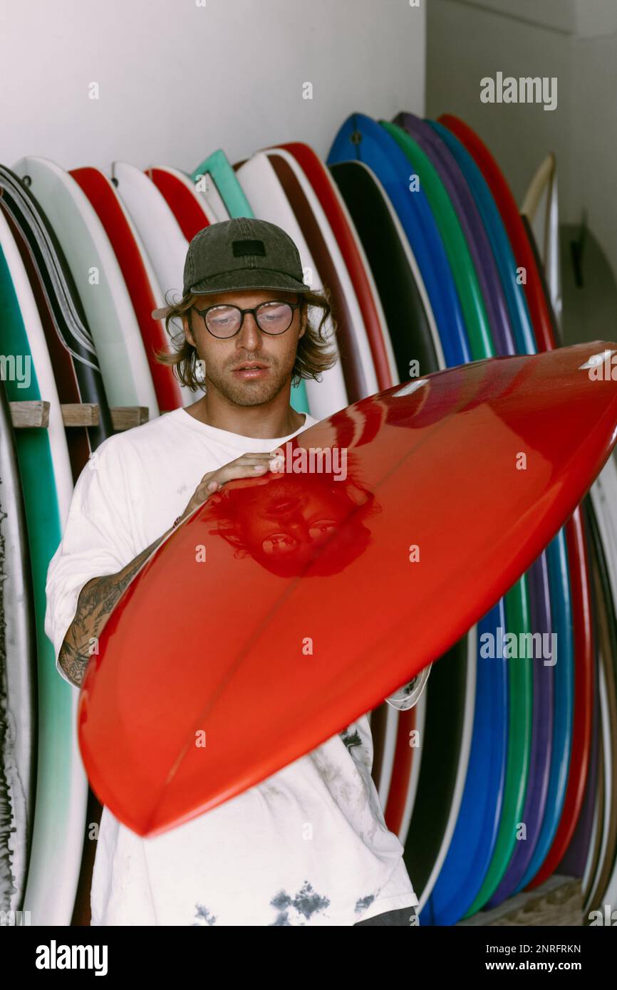 Man choosing a surfboard in a surfboard shop Stock Photo - Alamy