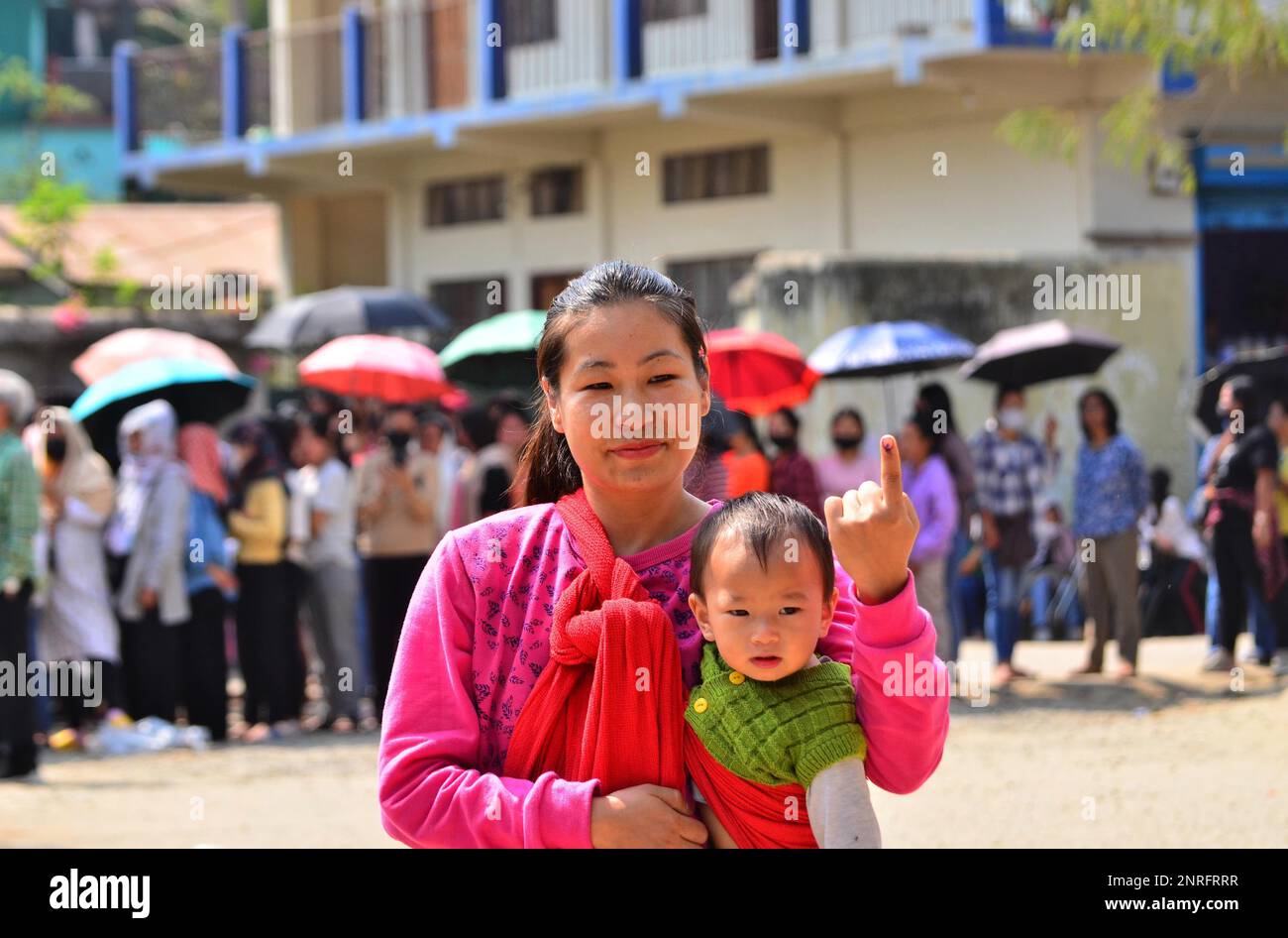 Dimapur, India. 27th Feb, 2023. A women voter carrying her child shows ...
