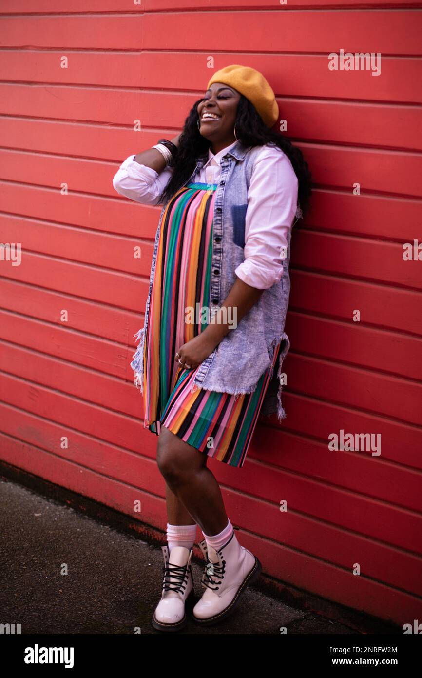 Person of Color leaning against a red wall with lots of color and joy ...