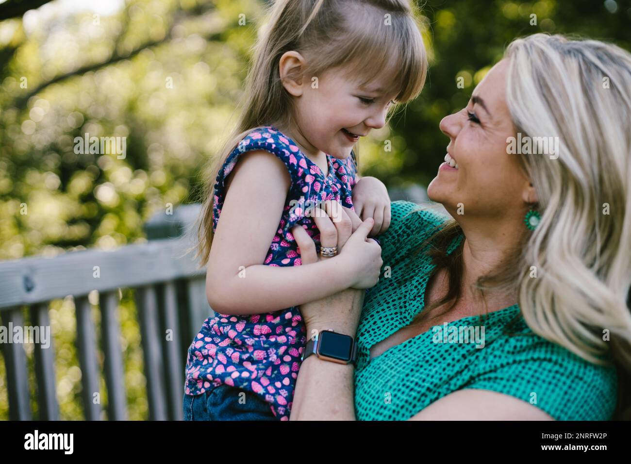 Mother smiles and tickles child daughter in forest gorgeous light Stock ...