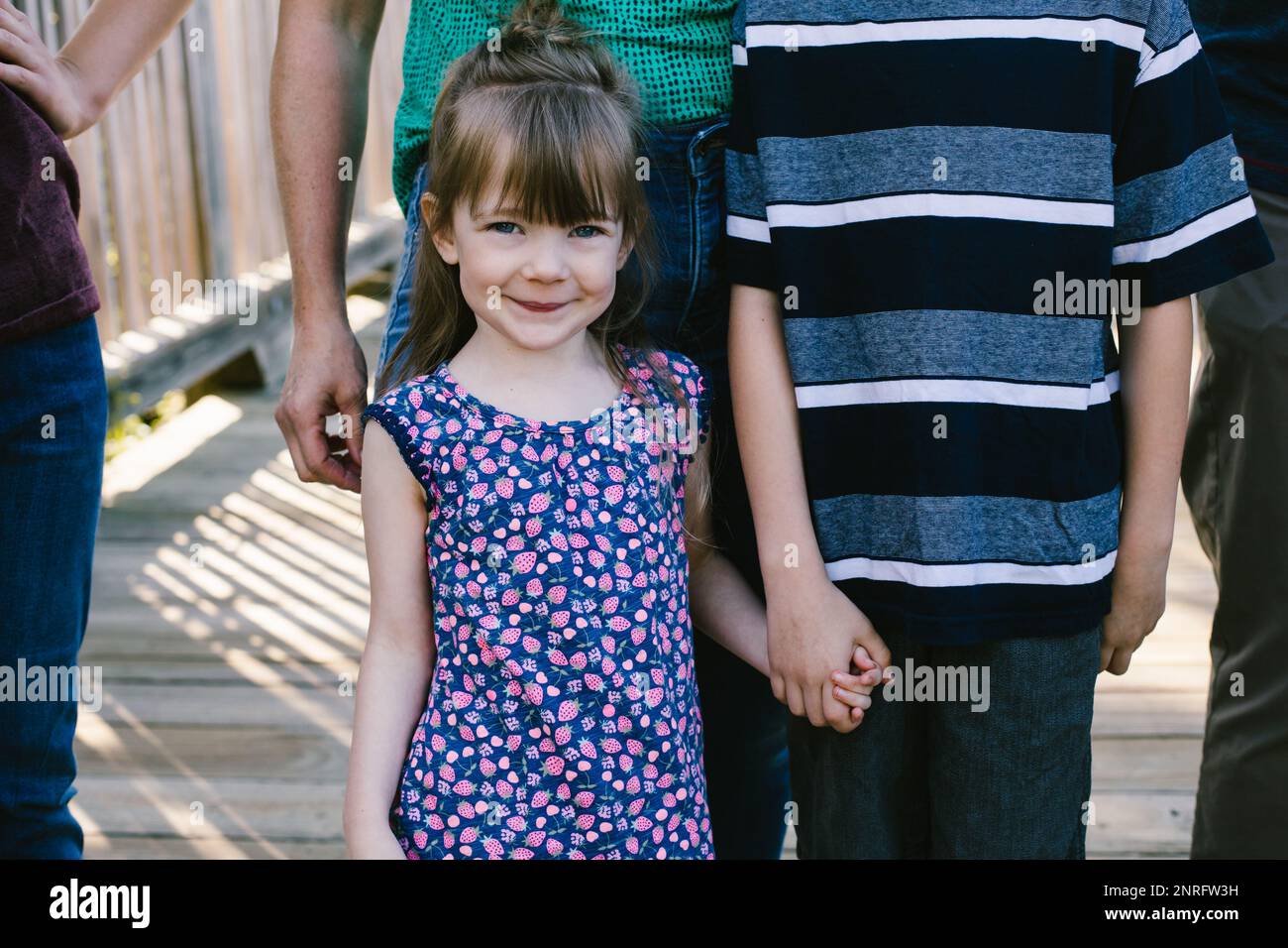 Sister holds brothers hand with family and smiles Stock Photo - Alamy
