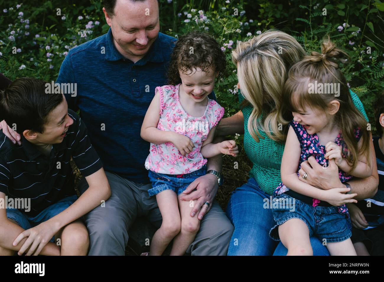 Parents hug and laugh with small children outside in summer Stock Photo ...