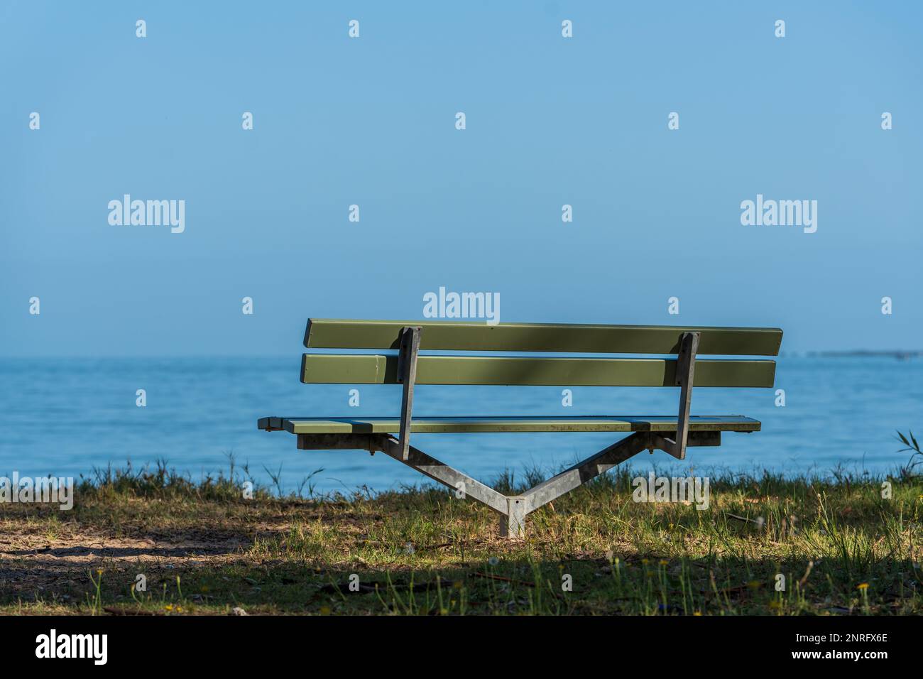 Bench seat by the waters edge with a view across the sea to the horizon ...