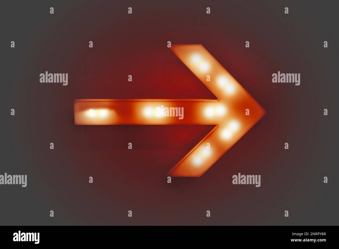 Red illuminated arrow on a wall in grey ambiance Stock Photo - Alamy