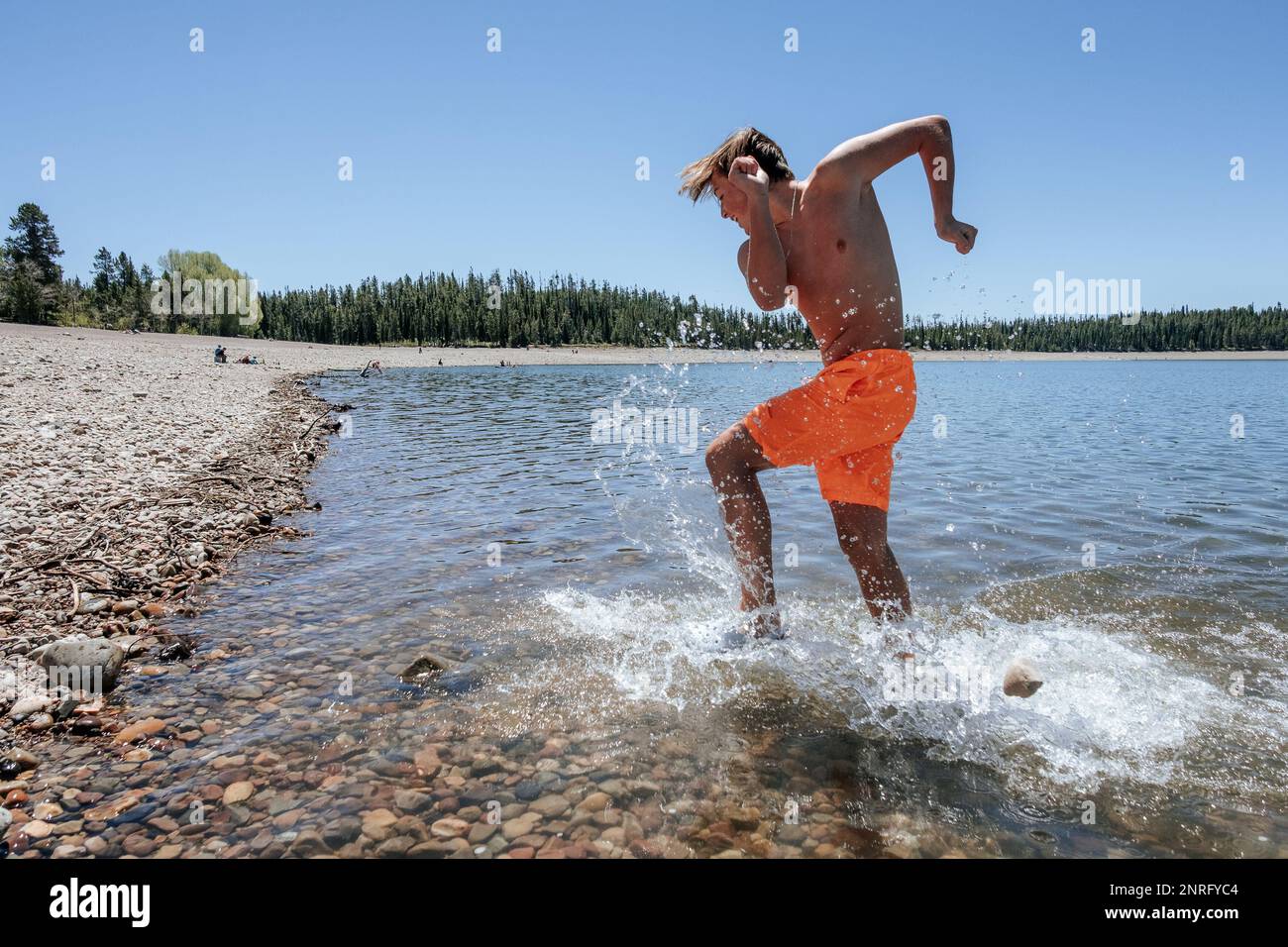 Teen boy splashing water in lake Stock Photo - Alamy