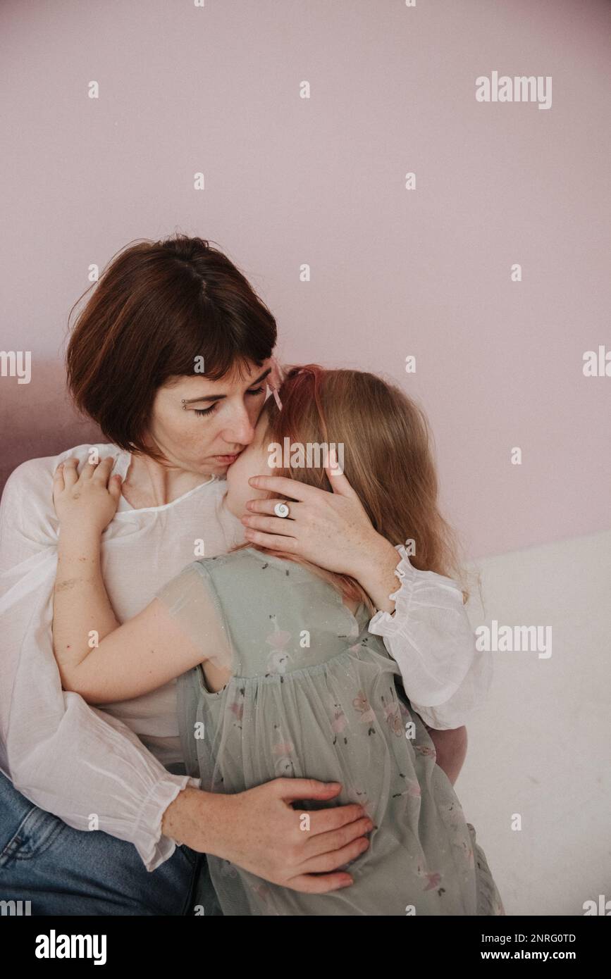 mom hugging daughter on pink background Stock Photo - Alamy