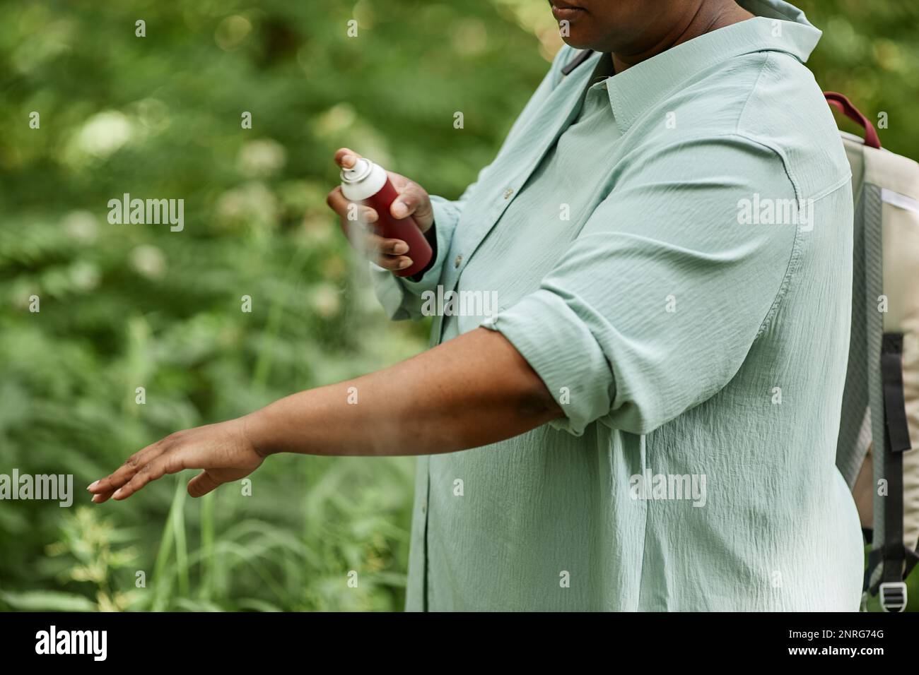 Side view closeup of black woman spraying arms with bug repellent ...