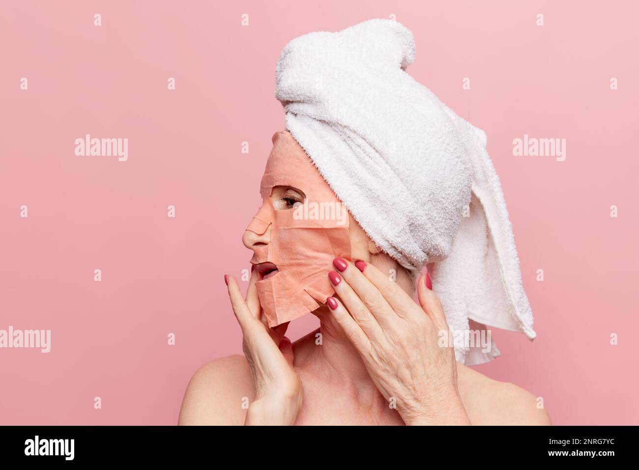 Beautiful middle-aged woman over pink studio background. After shower ...