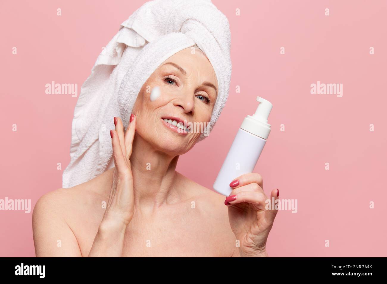 Beautiful middle-aged woman cleaning face with cleanser foam. Model ...