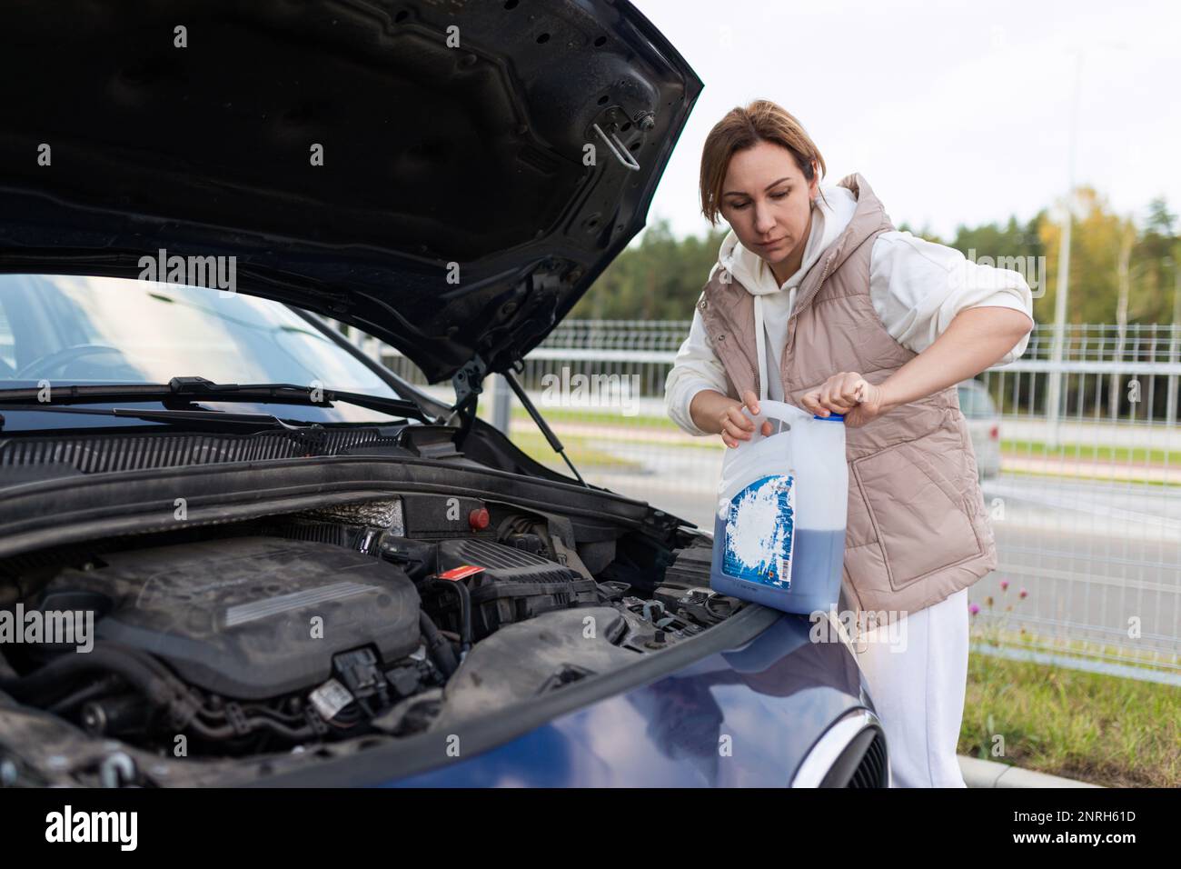 adult caucasian woman pours coolant into car Stock Photo - Alamy
