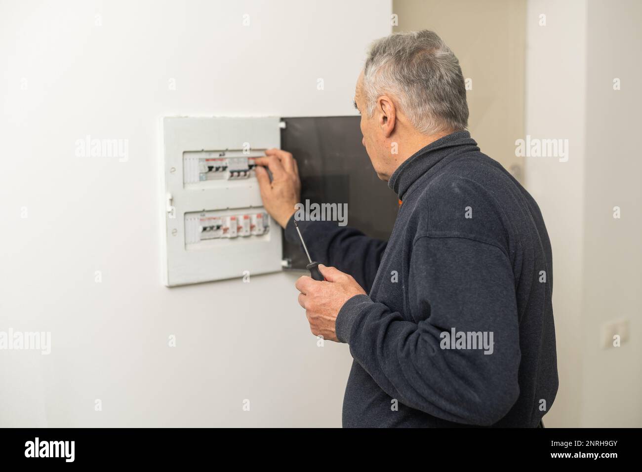 Elder man fixing an electric meter Stock Photo - Alamy
