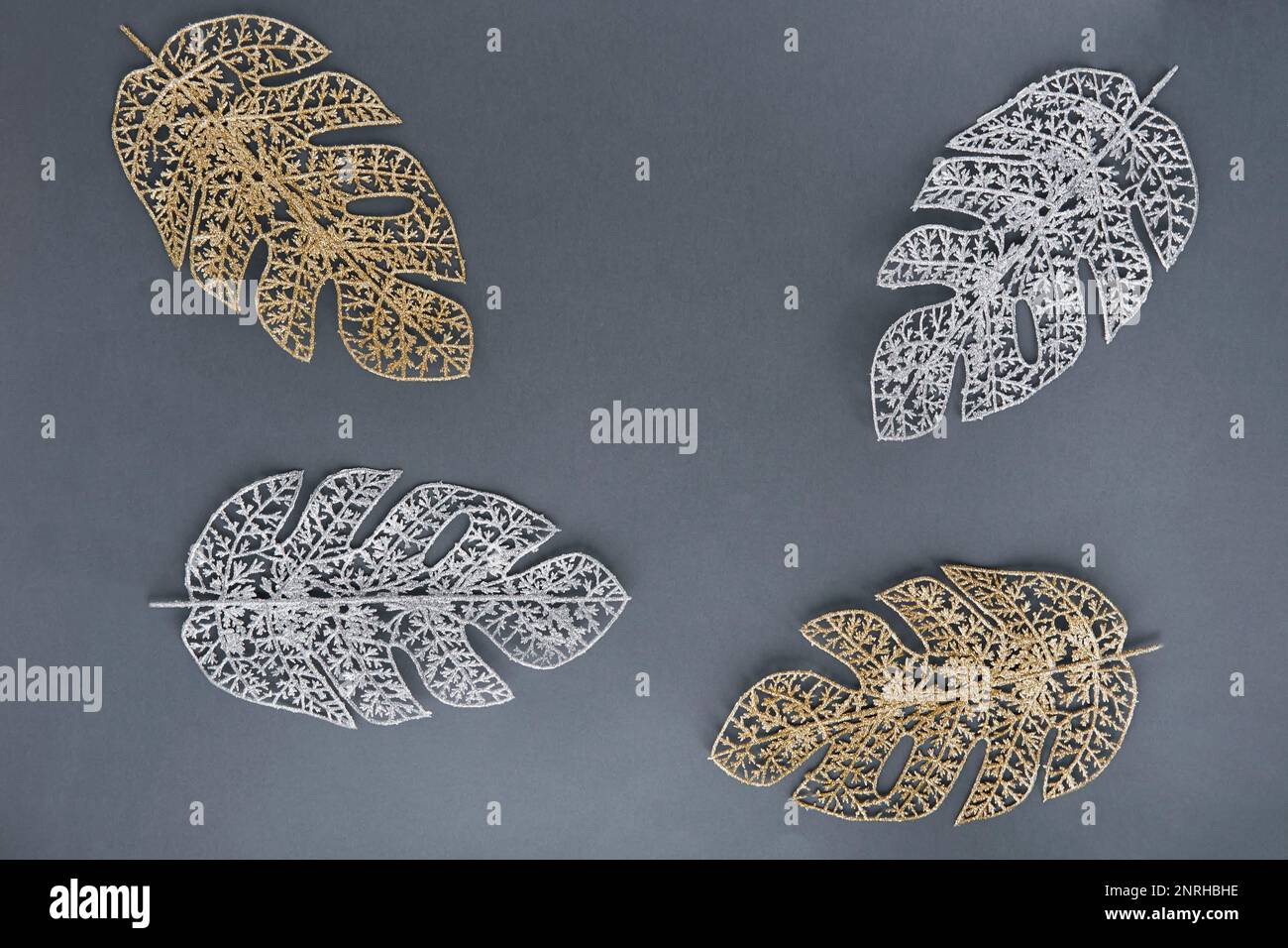 Monstera leaves from wire covered with gold and silver glitter on gray ...