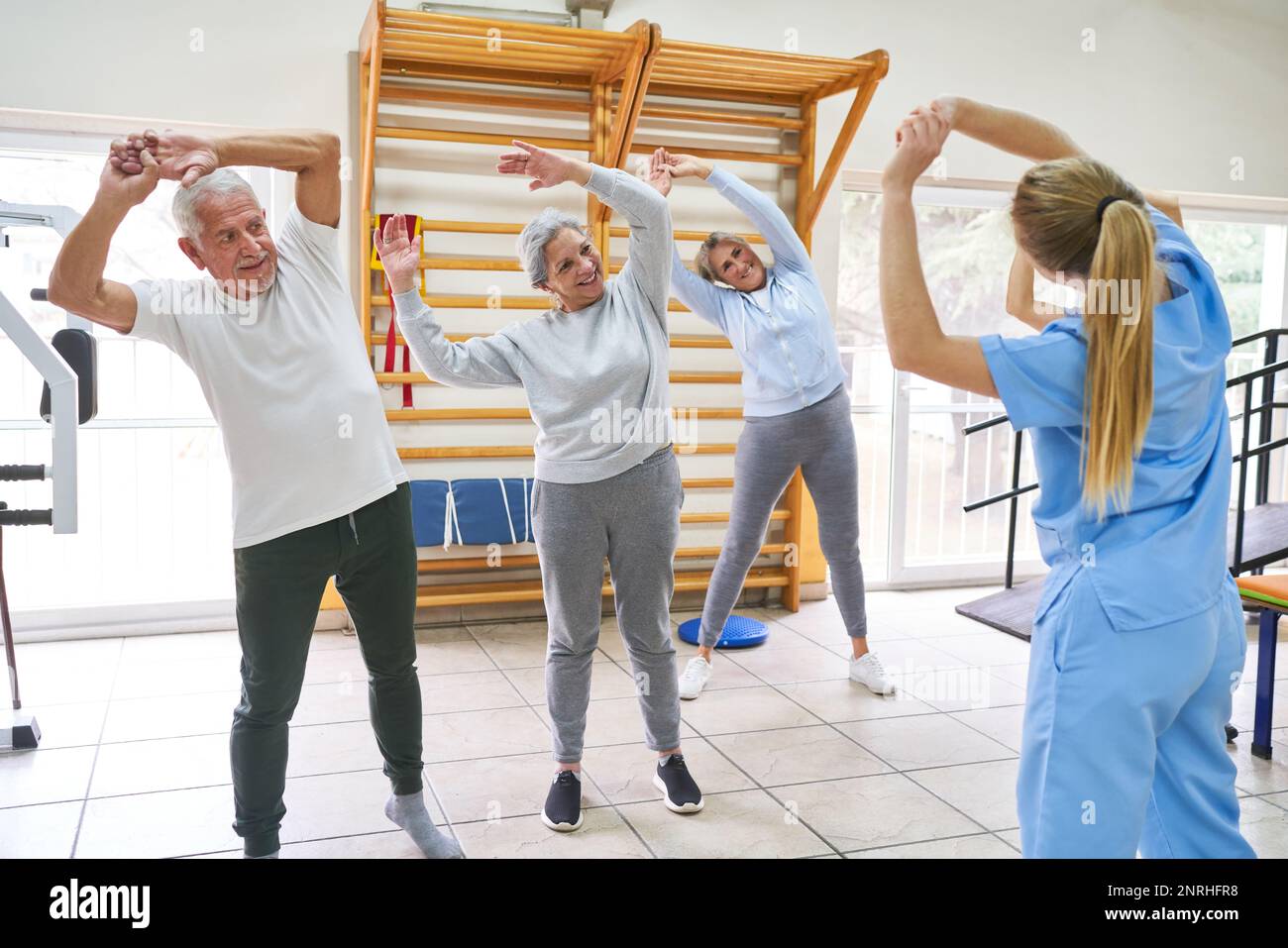 Group of elderly people working out in fitness class of nursing home ...